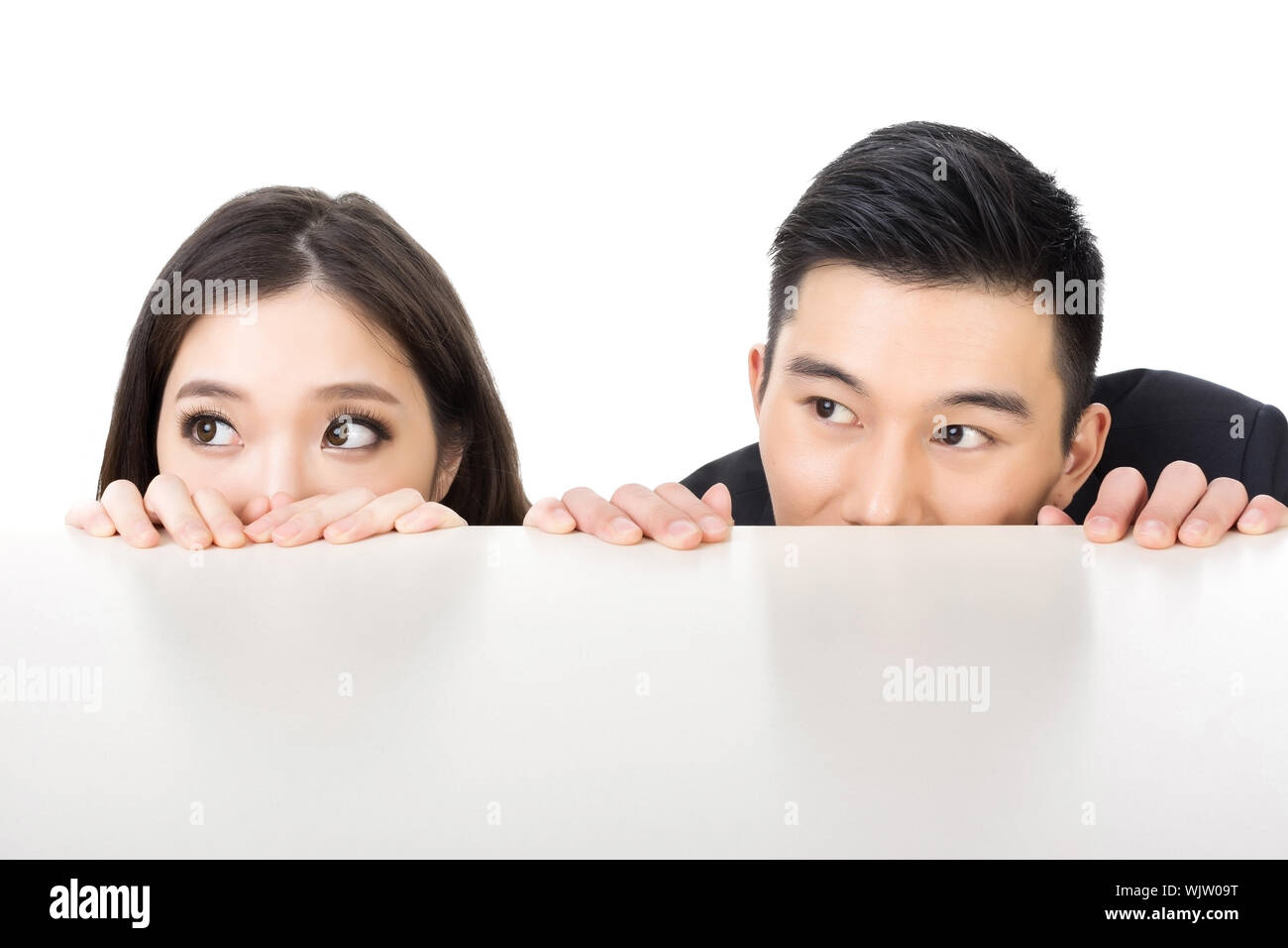 Asian business man and woman hide under the table and looking somewhere ...