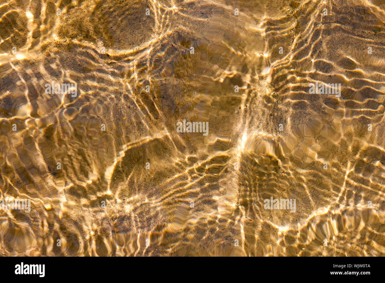 Sunny shallow water ripples over yellow sand bottom Stock Photo - Alamy
