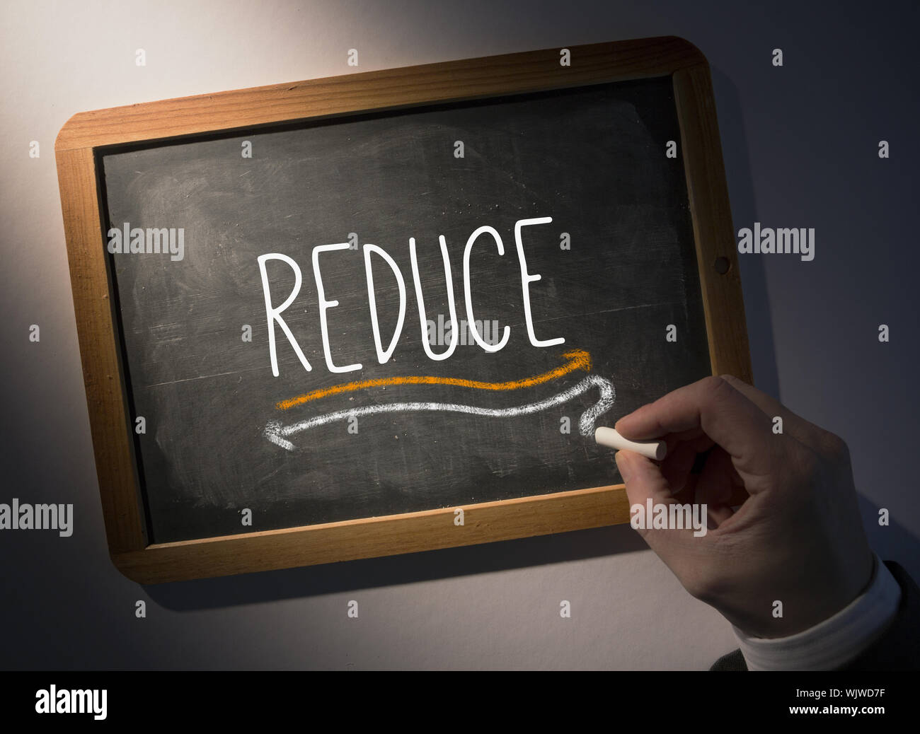 Hand writing the word reduce on black chalkboard Stock Photo - Alamy