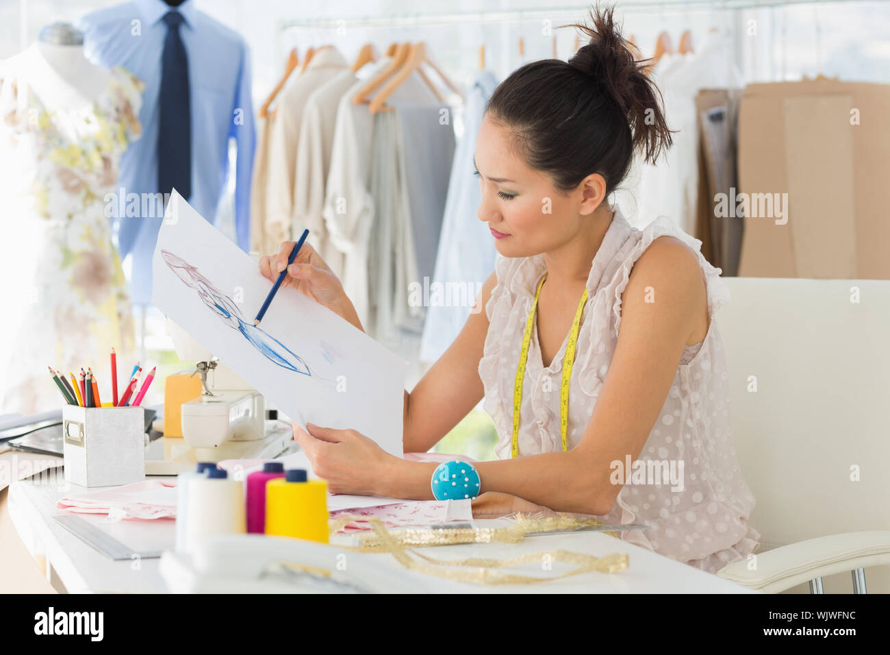 Side view of a young female fashion designer working on her designs in ...