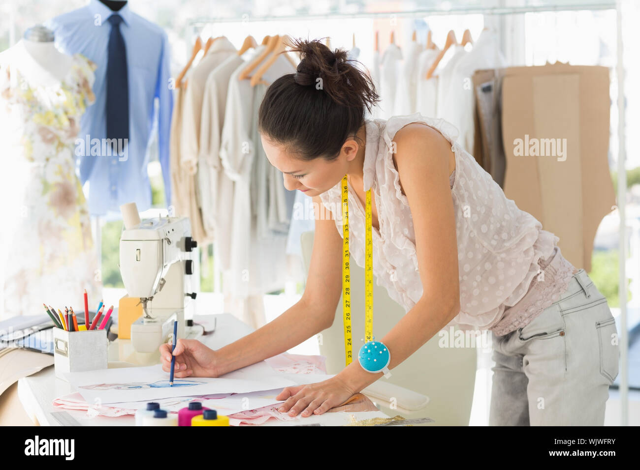 Side view of a young female fashion designer working on her designs in ...