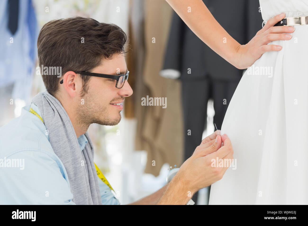 Closeup of a male fashion designer adjusting dress on model in the ...