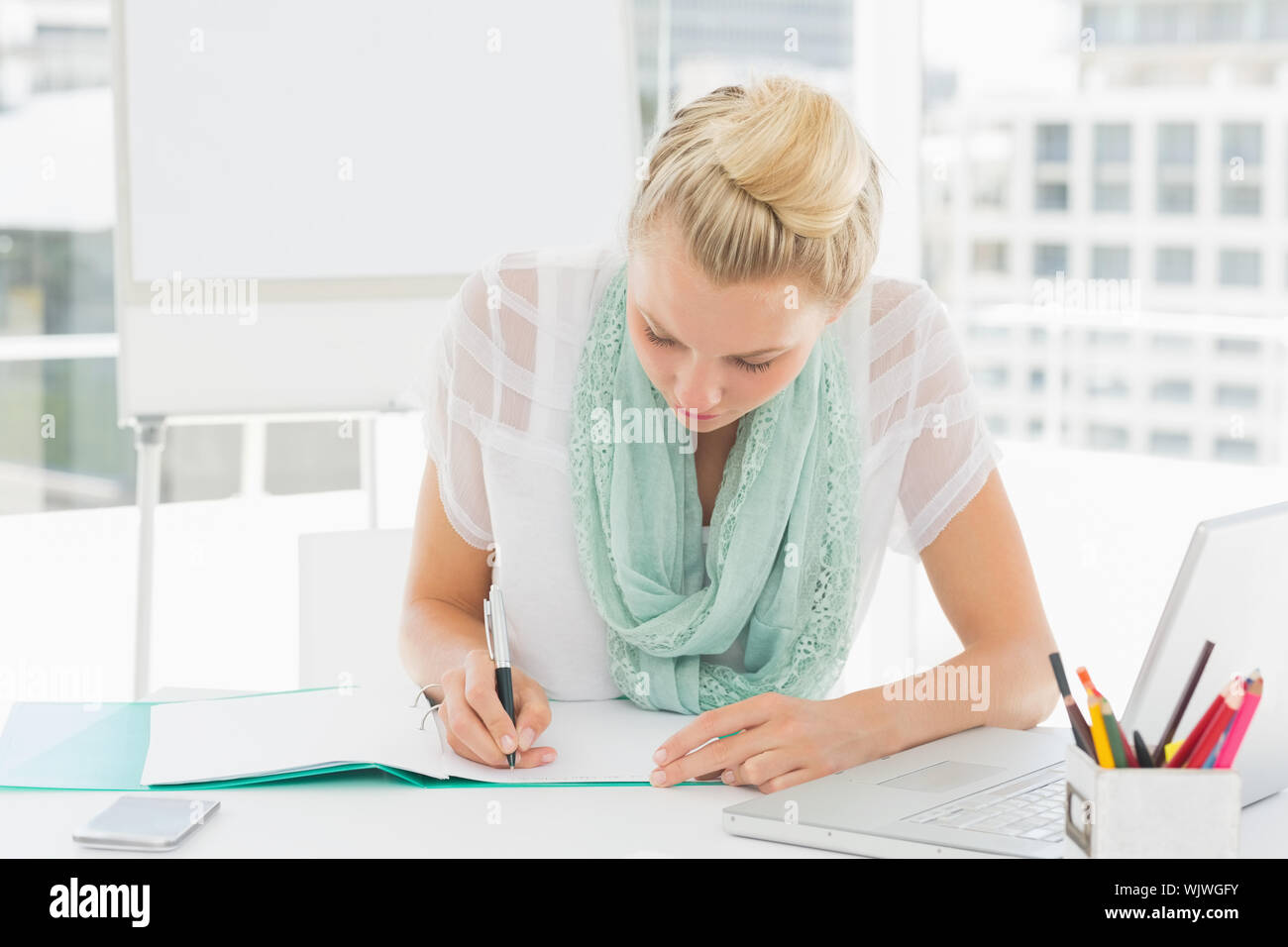 Casual young woman writing notes in a bright office Stock Photo - Alamy