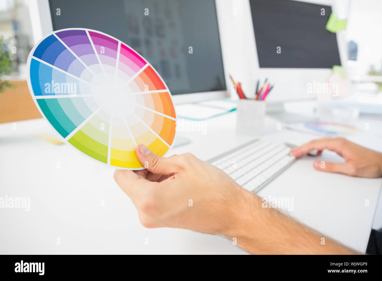 Closeup of hand holding color wheel while using computer at desk Stock ...