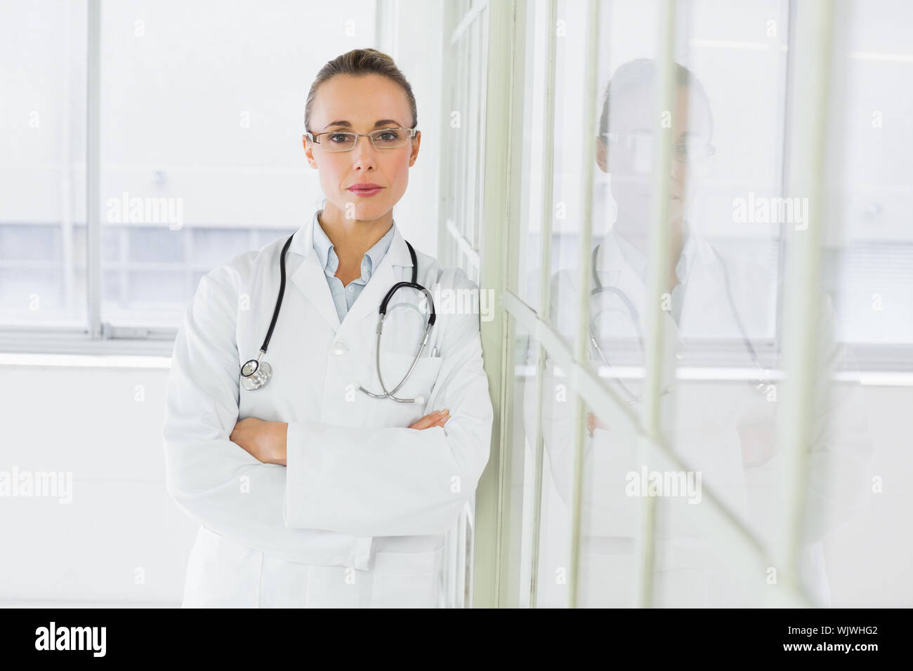 Portrait of a beautiful serious female doctor standing with arms ...