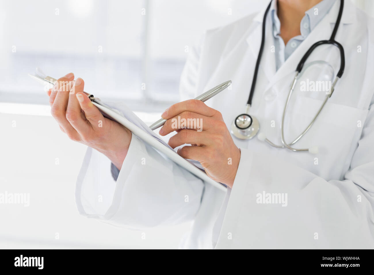 Closeup mid section of a female doctor writing reports in the hospital ...