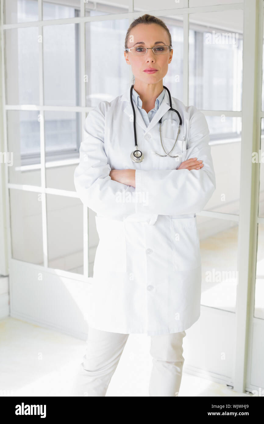 Portrait of a serious beautiful female doctor standing with arms ...