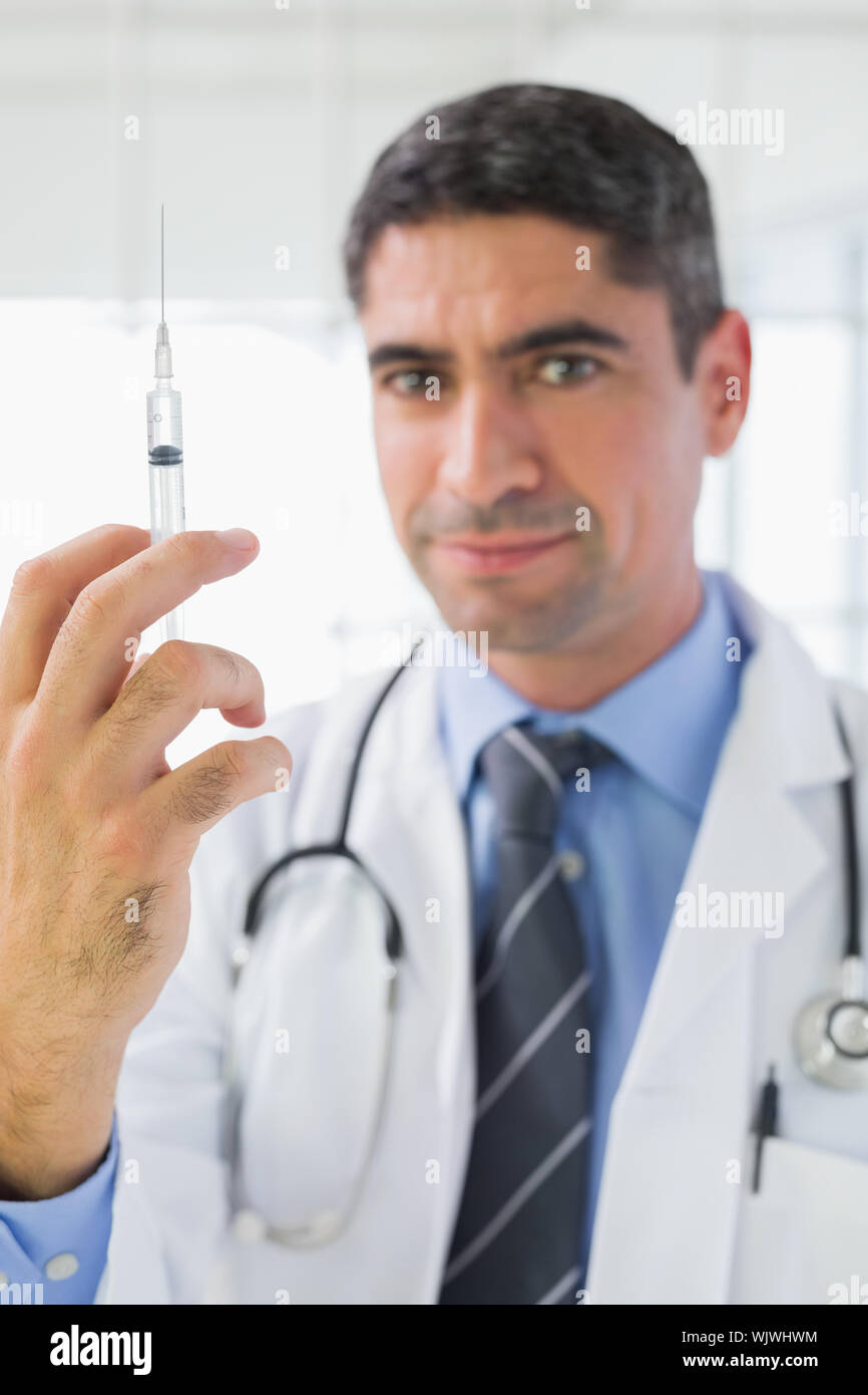 Portrait of male doctor holding an injection in the bright hospital ...