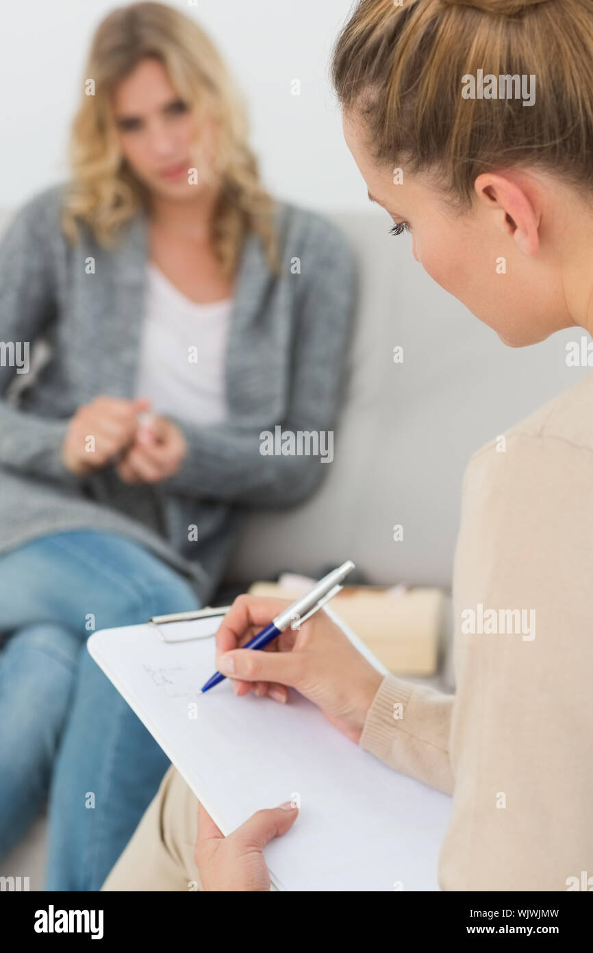 Therapist writing notes on her clipboard at therapy session Stock Photo ...