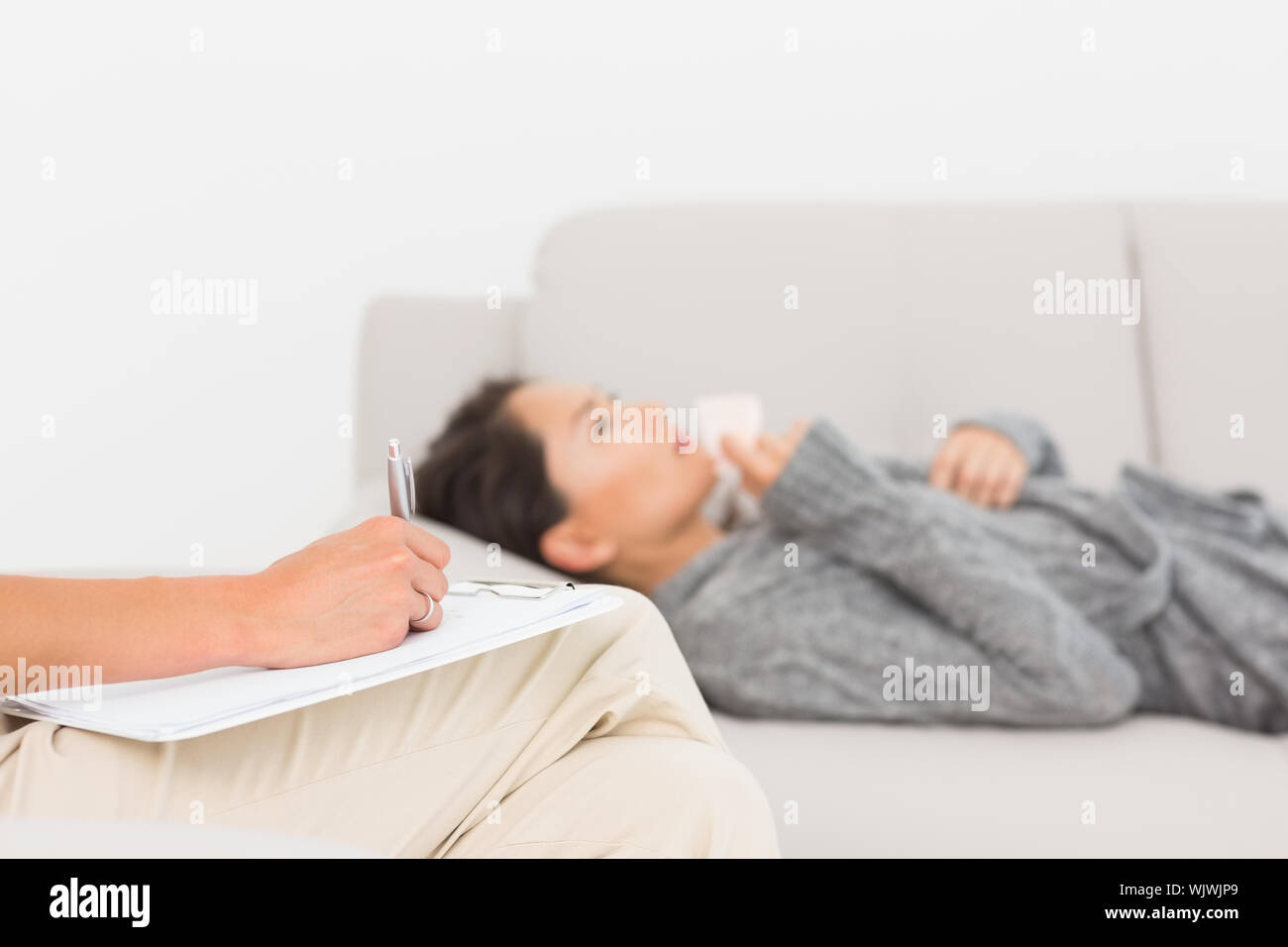 Therapist taking notes on her crying patient on the sofa at therapy ...