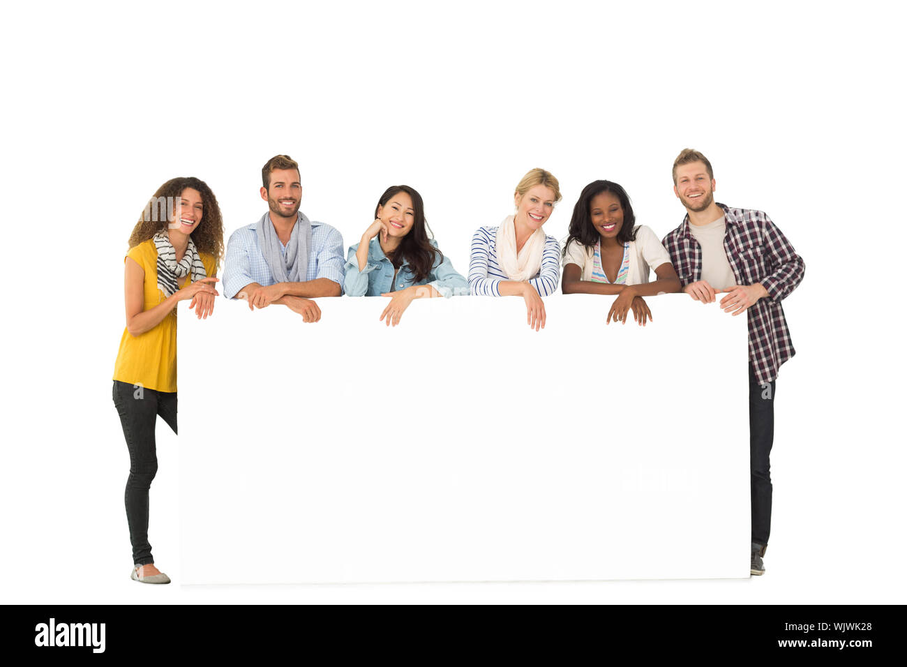 Smiling group of young friends leaning on large poster on white ...