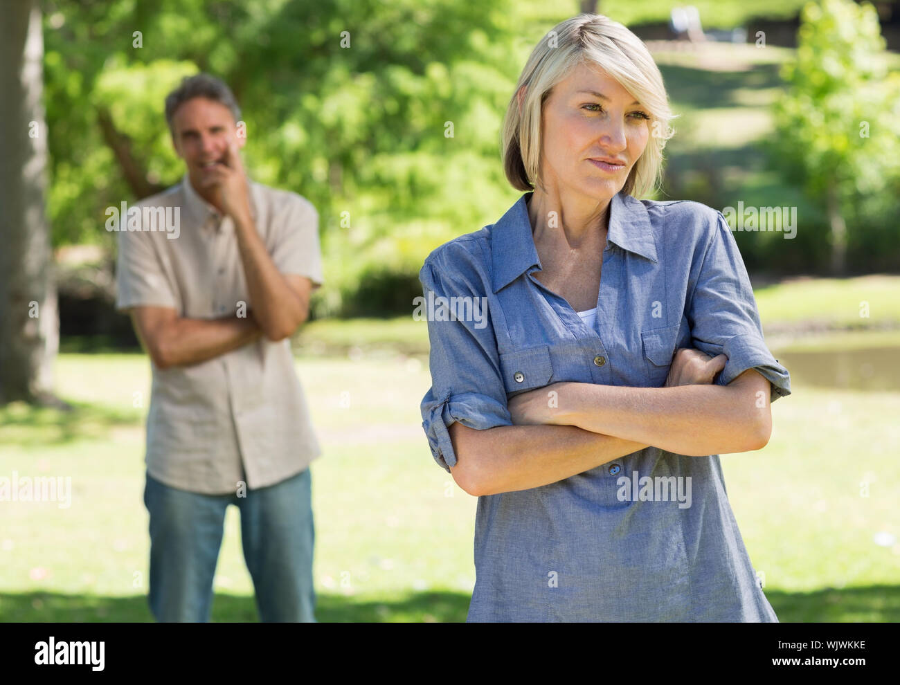 Sad woman with man in background at park Stock Photo - Alamy