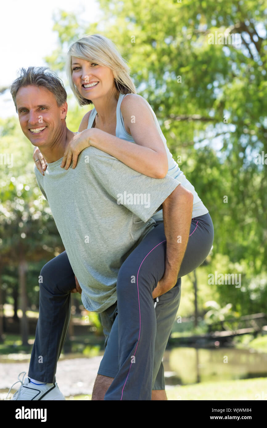 Portrait of loving man giving piggyback ride to woman in the park Stock ...