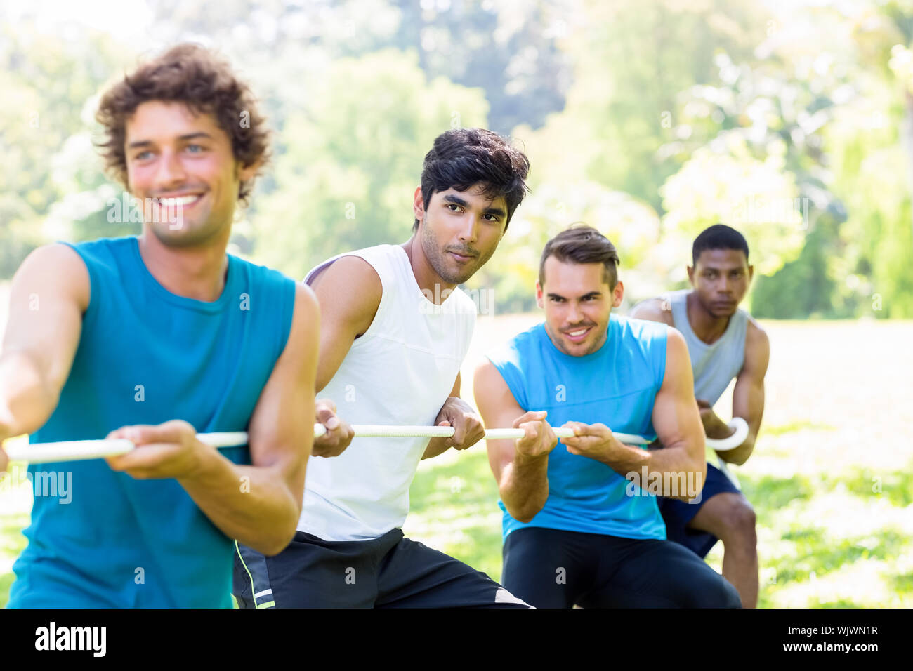 Multiethnic male friends playing tug of war in park Stock Photo - Alamy