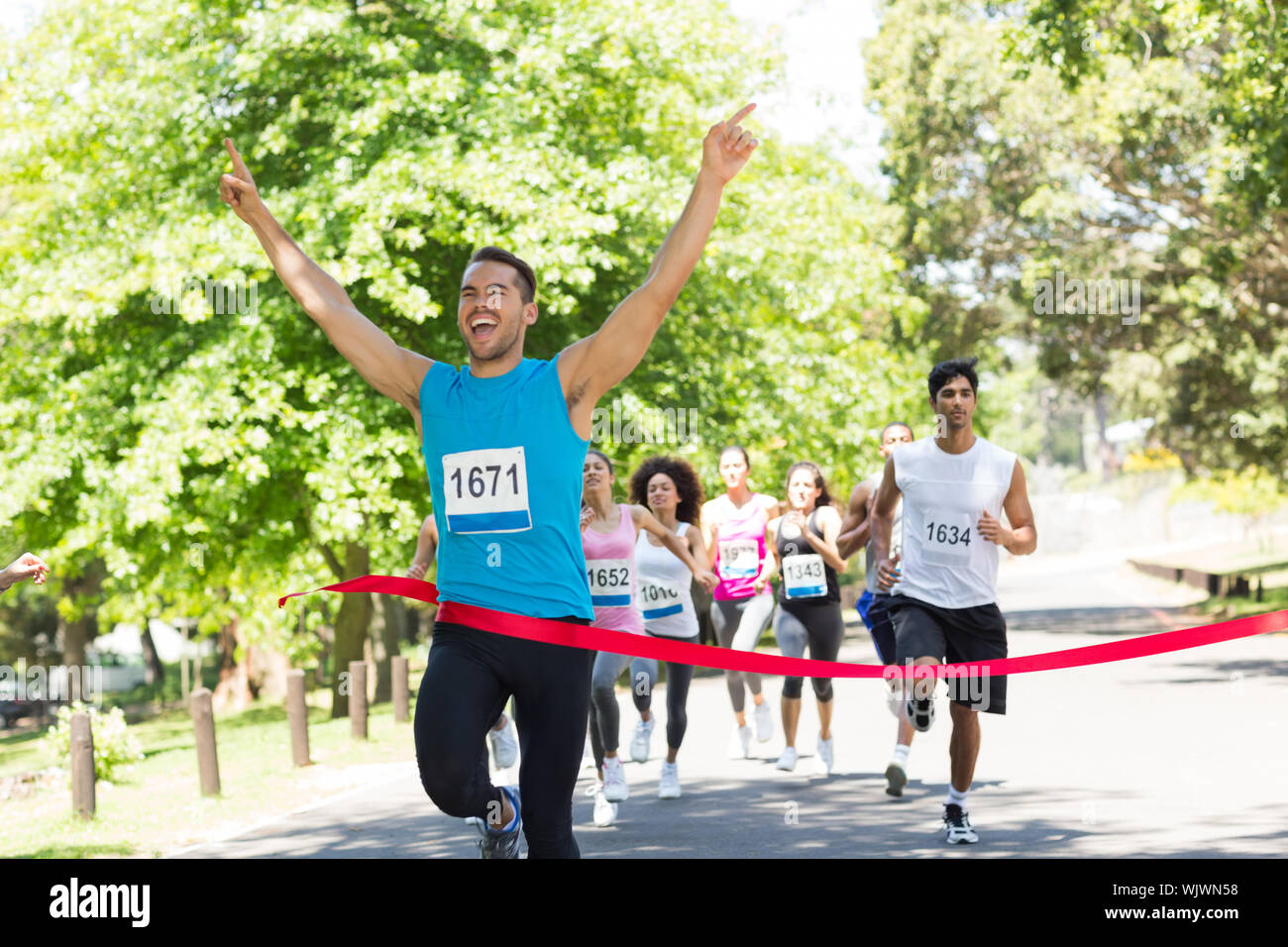 Excited male runner crossing the finshline of a marathon Stock Photo ...