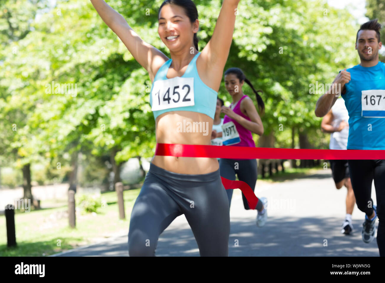 Female marathon winner with arms raised crossing finish line Stock ...