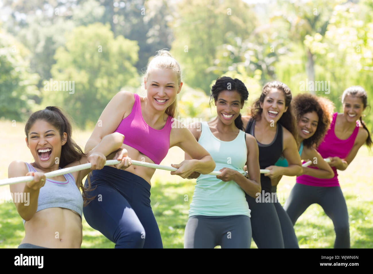 Happy women pulling a rope in tug of war at the park Stock Photo - Alamy