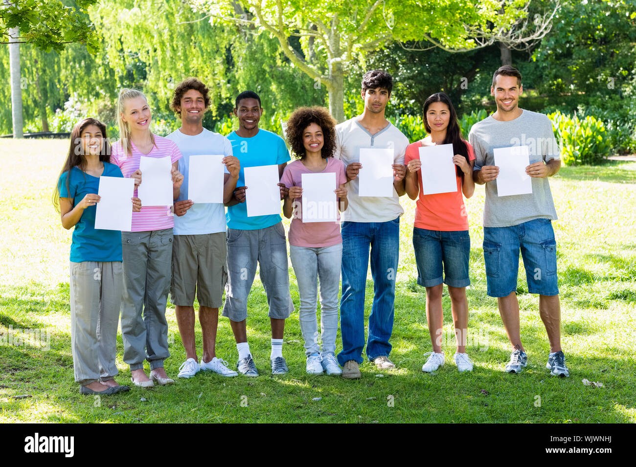 Portrait of confident university students holding blank papers on ...