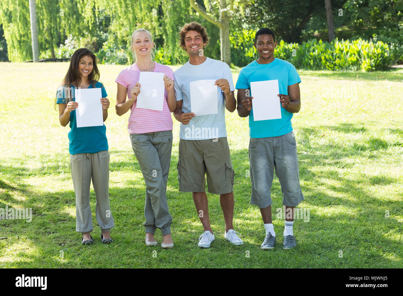 Portrait of happy friends holding blank papers on campus Stock Photo ...