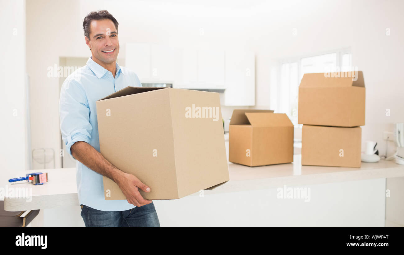 Portrait of a smiling man carrying boxes in a new house Stock Photo - Alamy