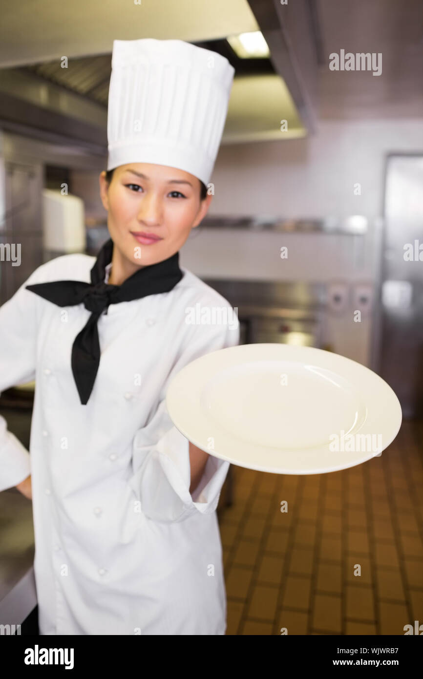 Portrait of a confident female cook holding an empty plate in the ...