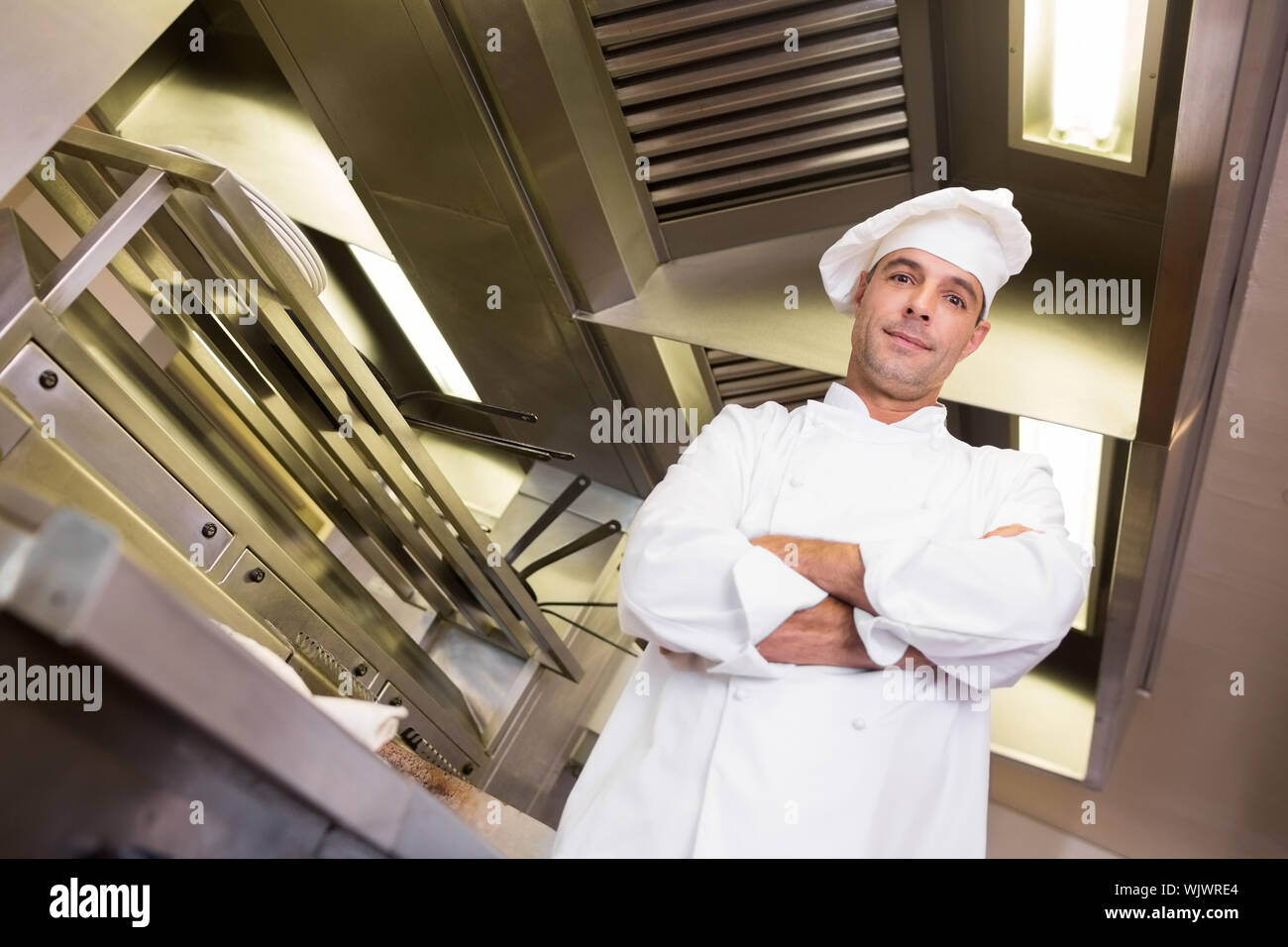 Portrait of a smiling male cook with arms crossed standing in the ...
