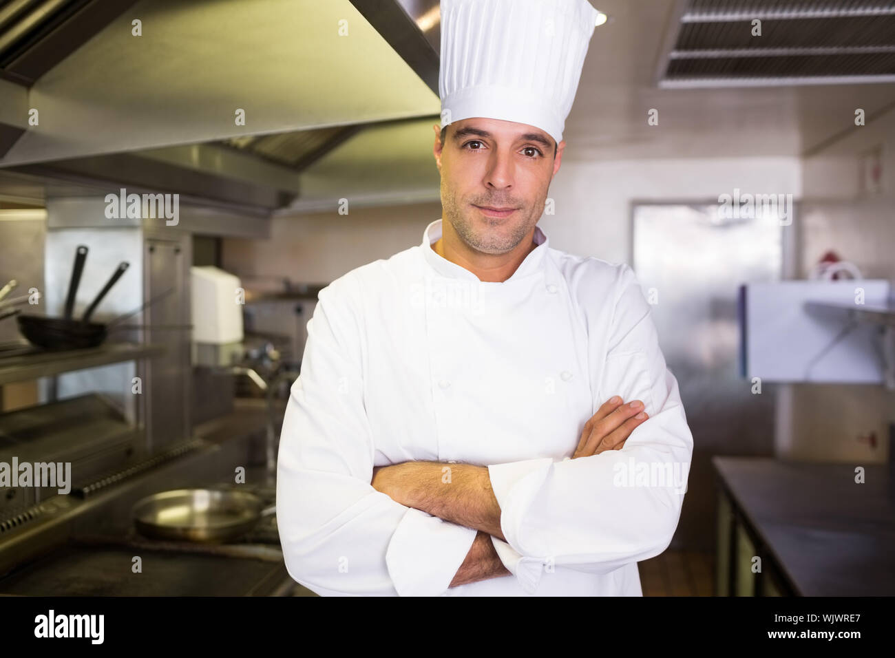 Portrait of a smiling male cook with arms crossed standing in the ...