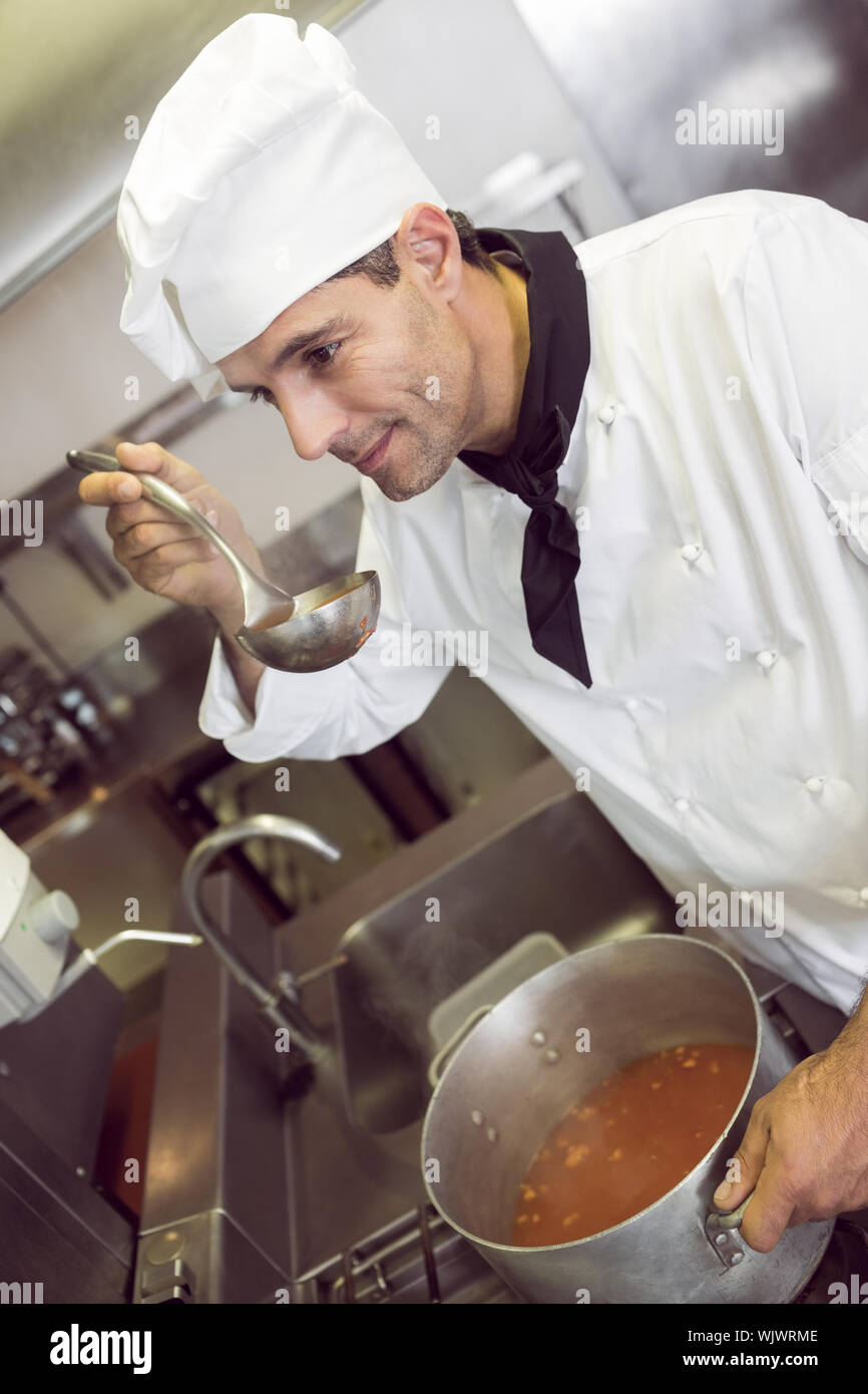 Concentrated young male cook tasting food in the kitchen Stock Photo ...