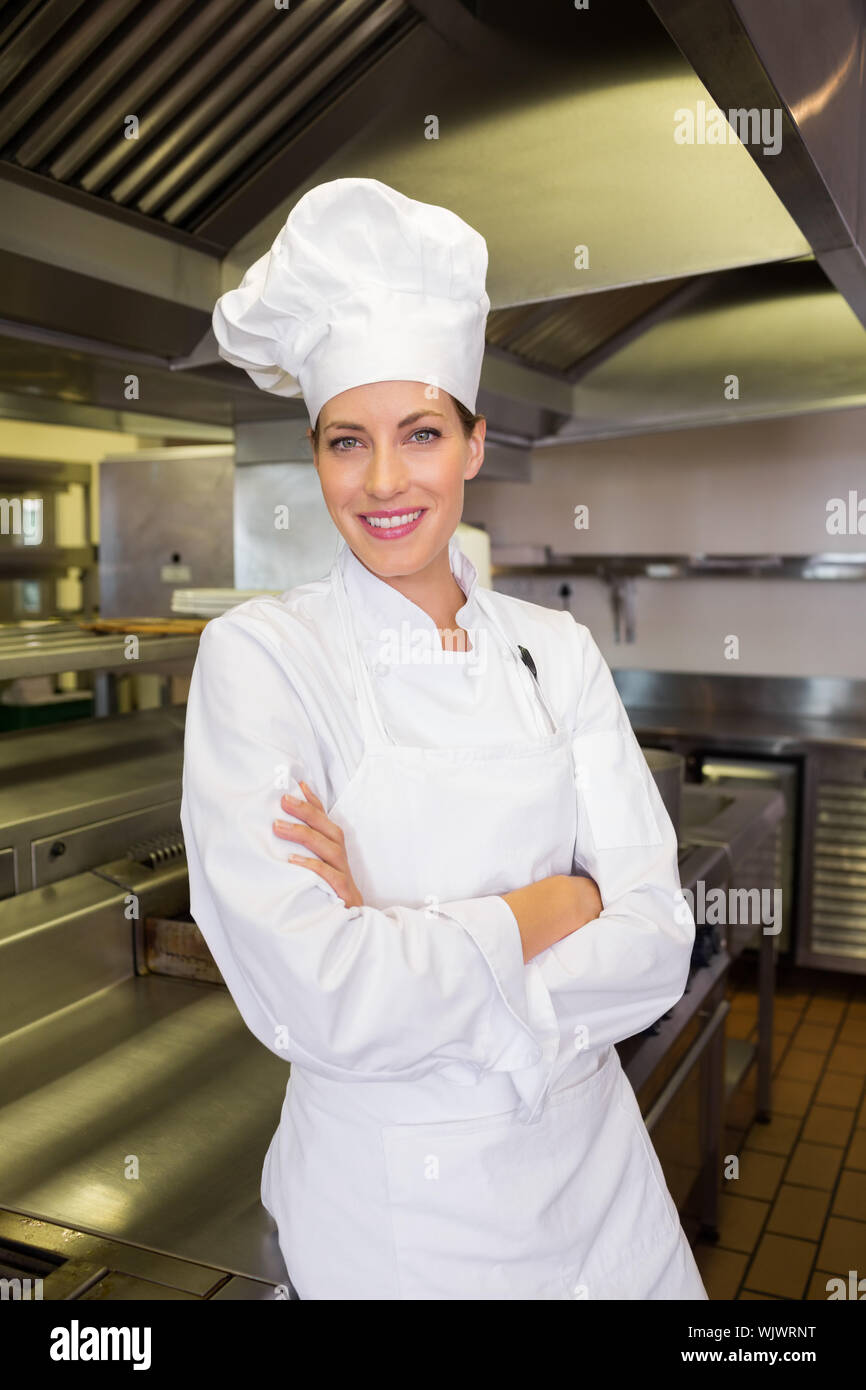 Portrait of a smiling female cook with arms crossed standing in the ...