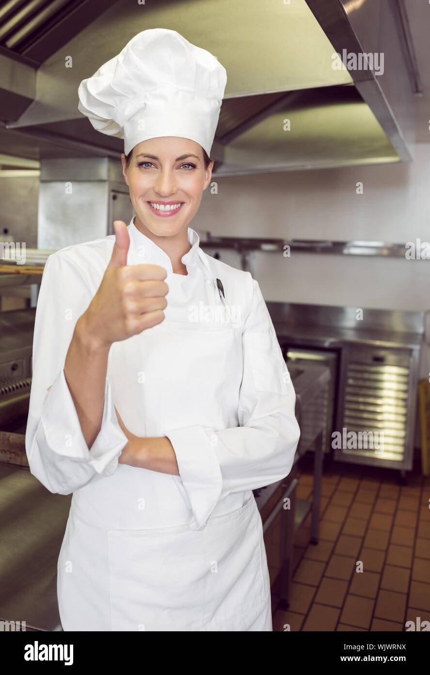 Portrait of a smiling female cook gesturing okay sign in the kitchen ...
