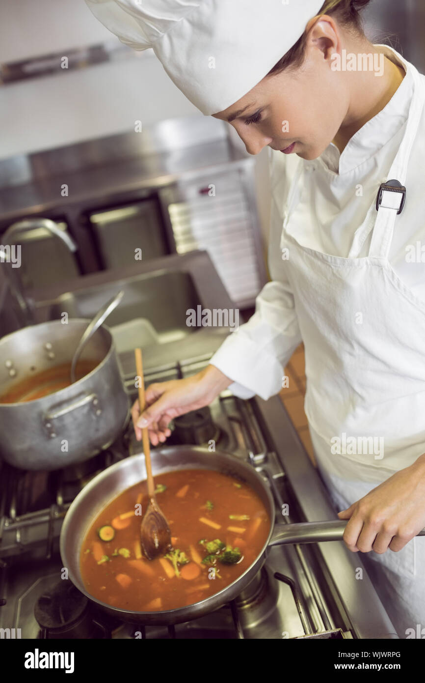Side view of a concentrated female cook preparing food in the kitchen ...