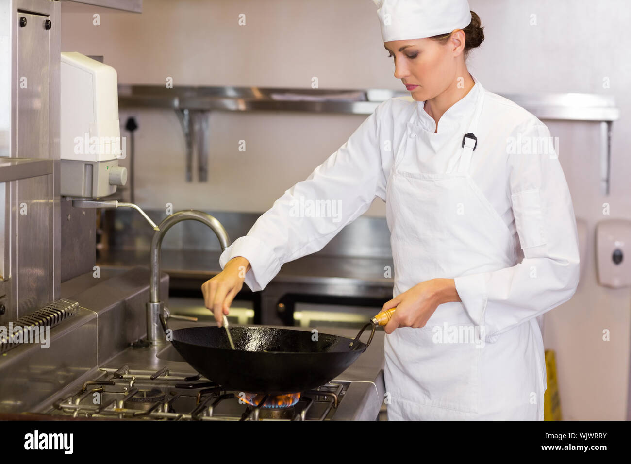 Side view of a concentrated female chef preparing food in the kitchen ...