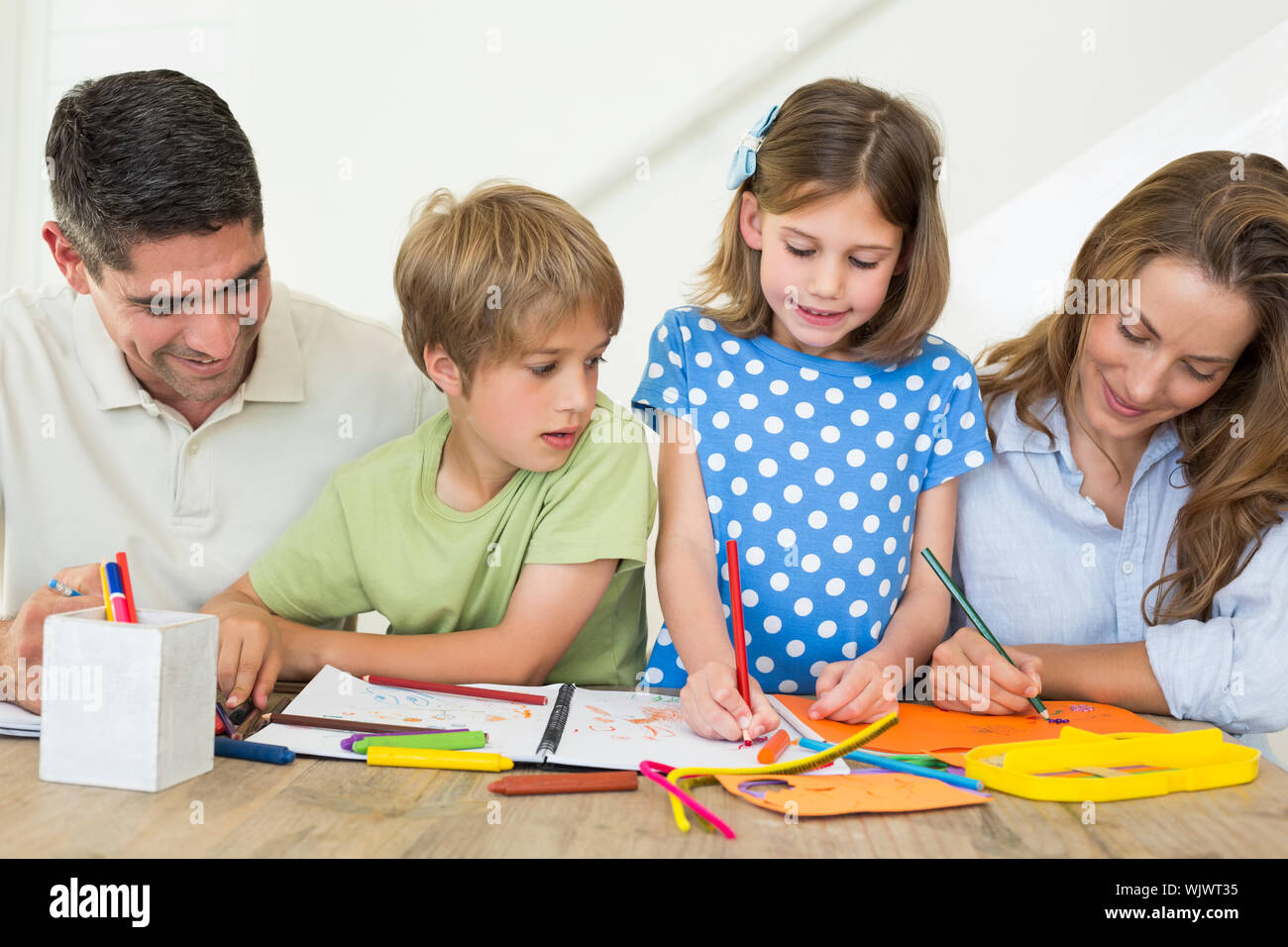 Parents and siblings coloring together at home Stock Photo - Alamy