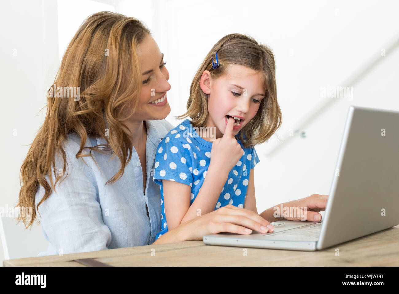 Mother teaching daughter to use laptop at home Stock Photo - Alamy