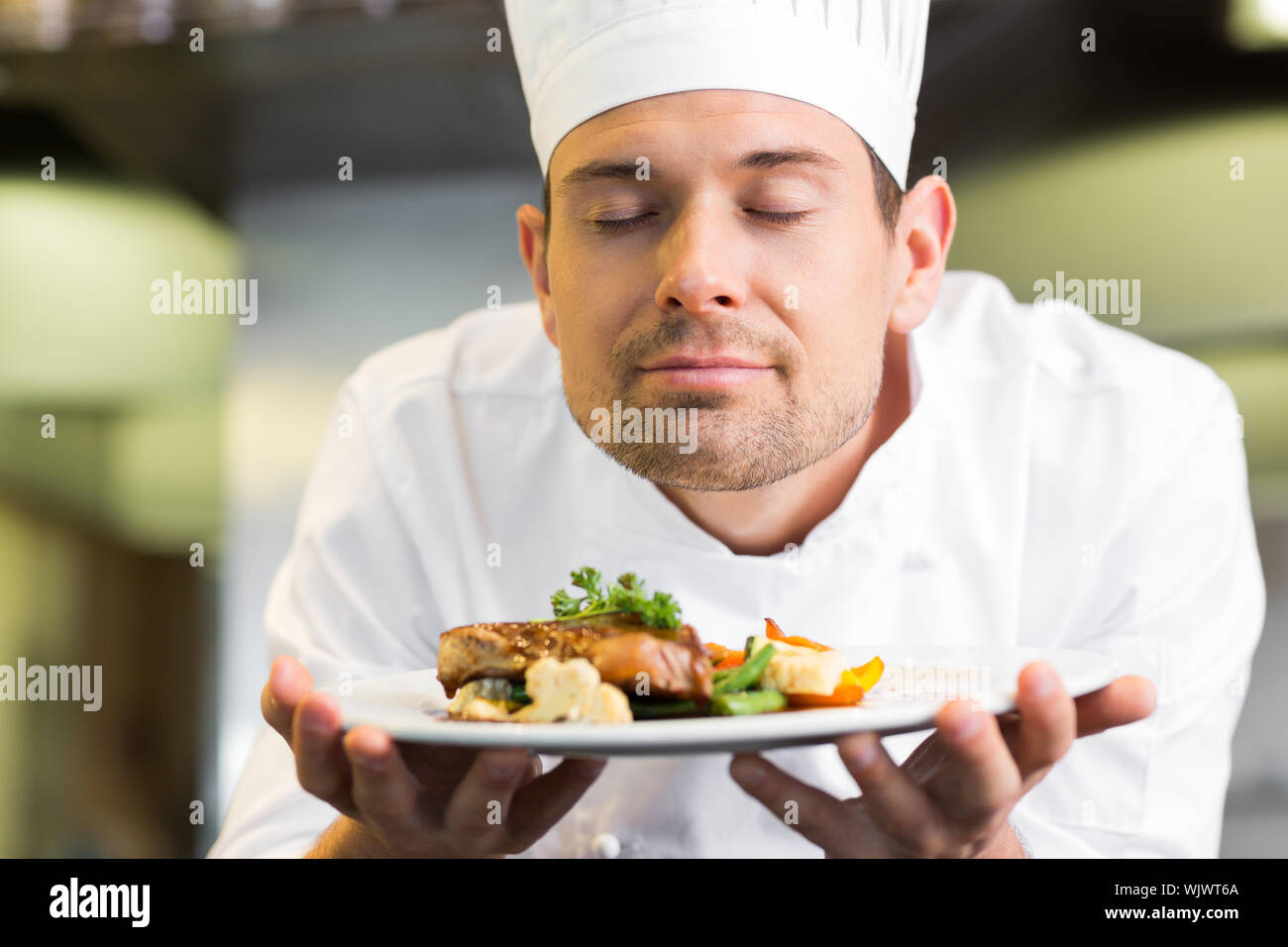 Closeup of a male chef with eyes closed smelling food in the kitchen ...
