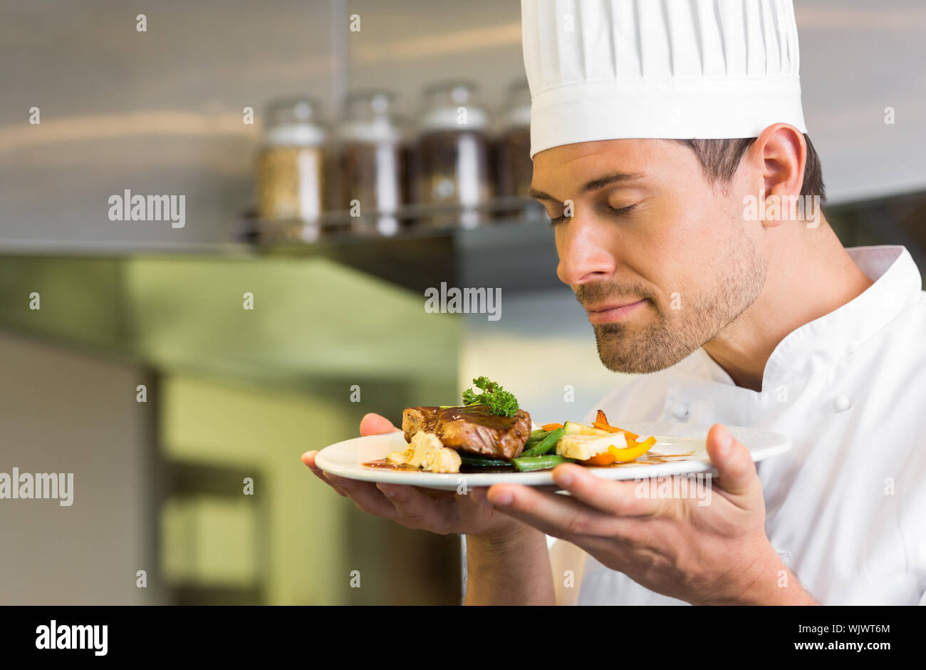 Closeup of a male chef with eyes closed smelling food in the kitchen ...