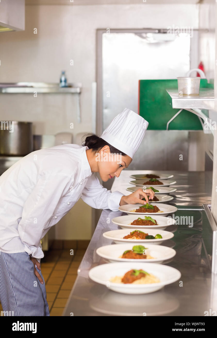 Side view of a concentrated female chef preparing food in the kitchen ...