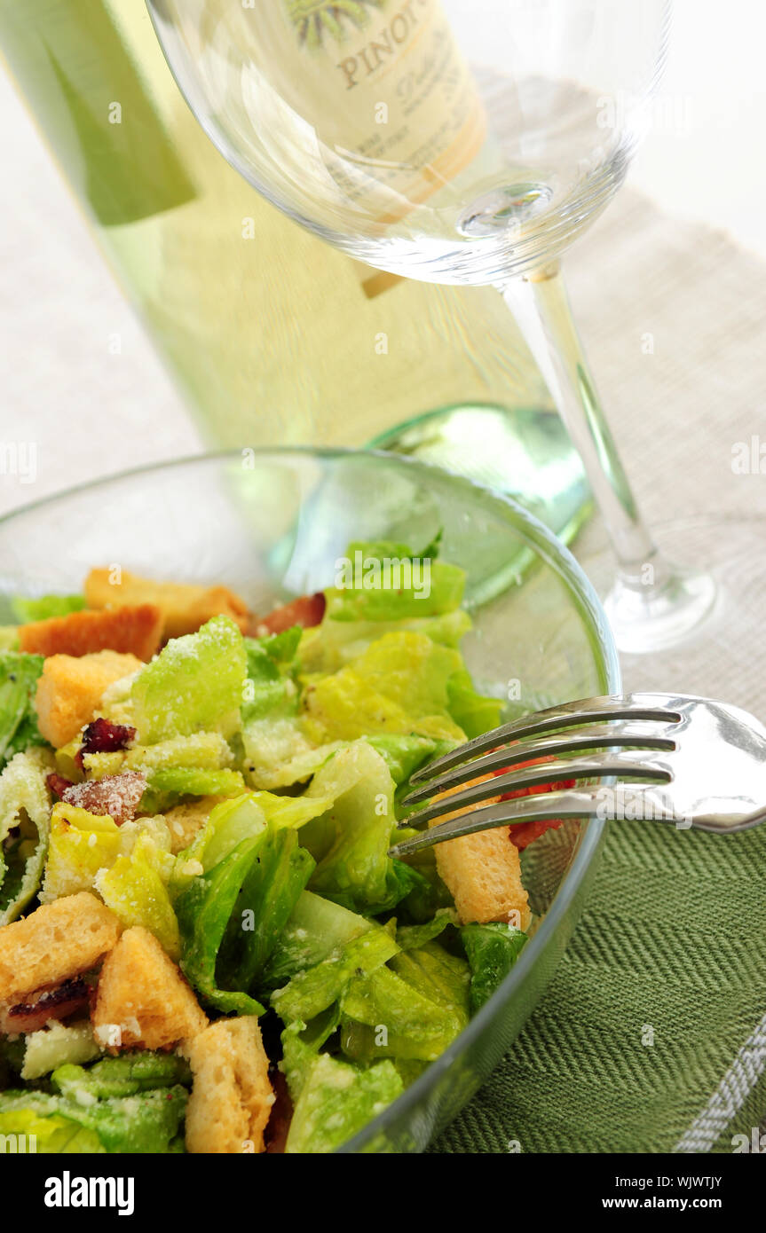 Caesar salad served in a glass bowl and white wine Stock Photo - Alamy