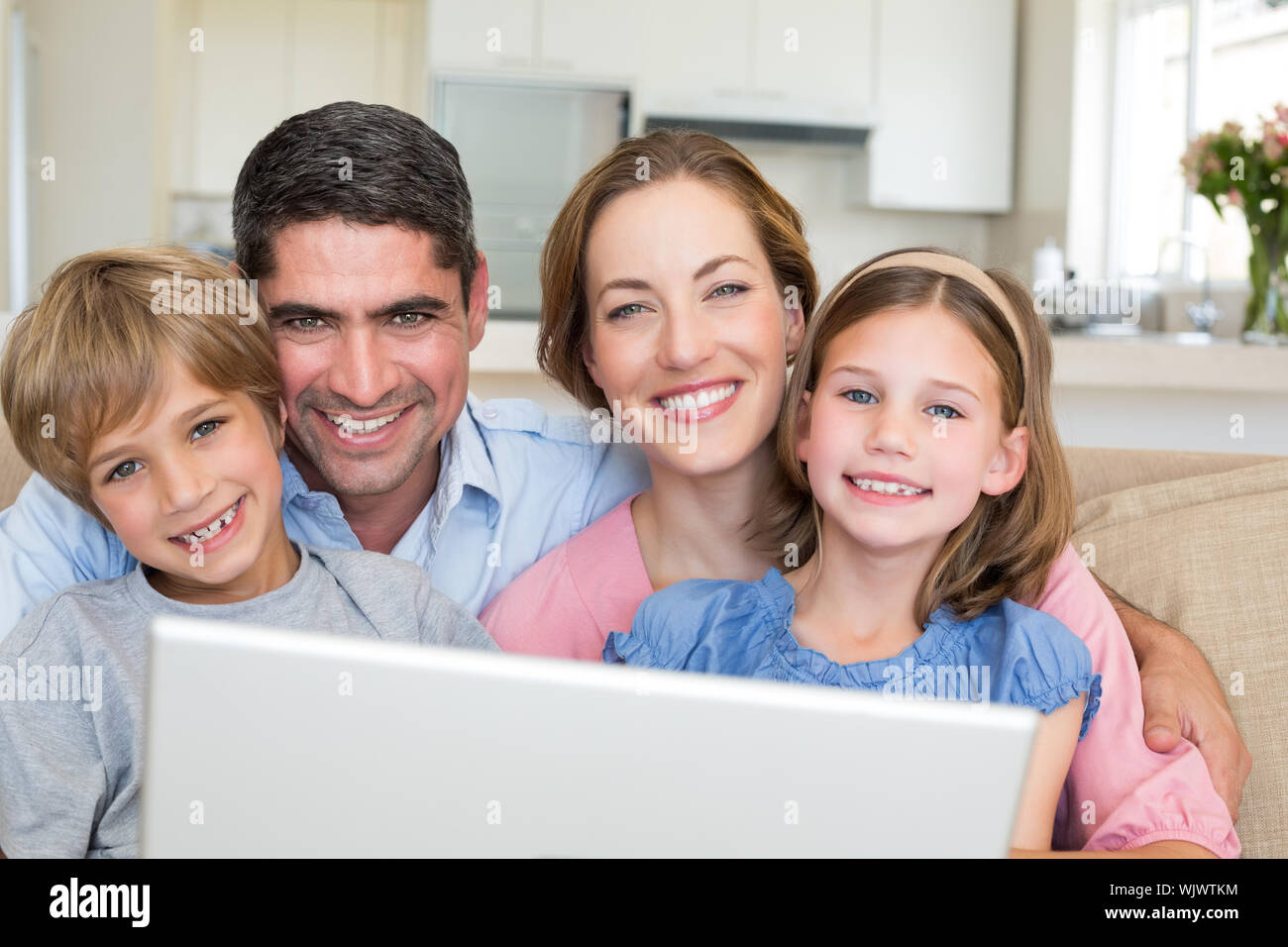 Closeup portrait of smiling family with laptop in house Stock Photo - Alamy