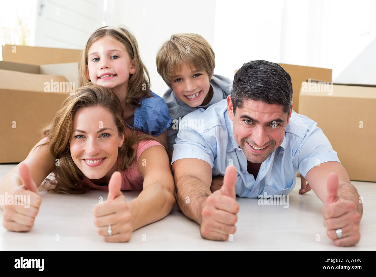 Portrait of happy family showing thumbs up sign while lying in their ...