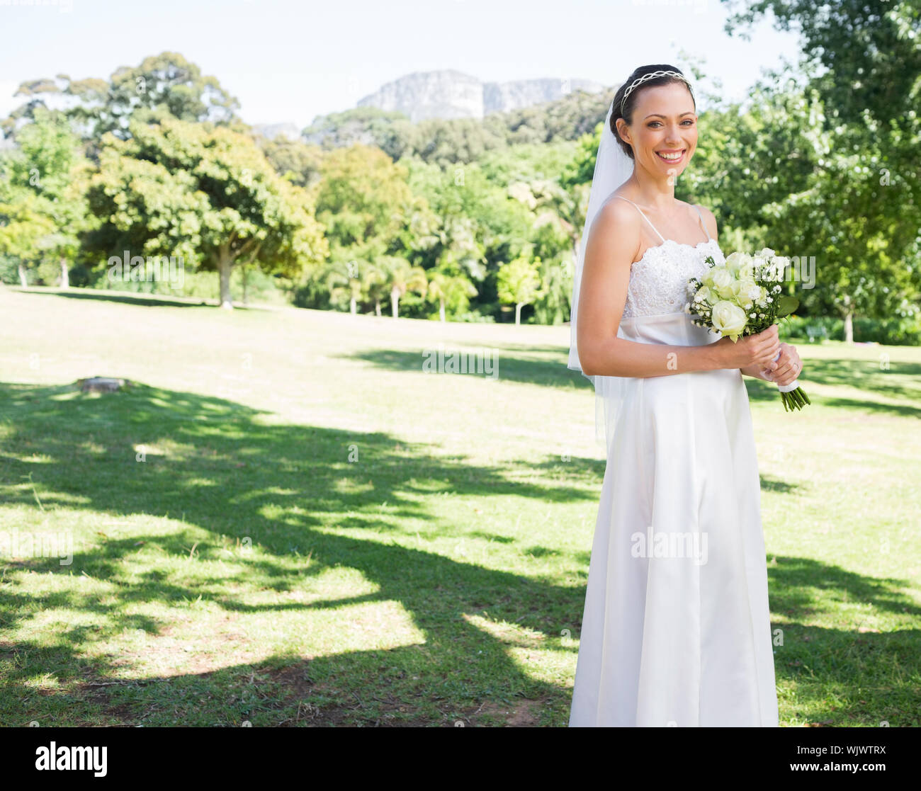 Portrait of happy bride holding flower bouquet in garden Stock Photo ...