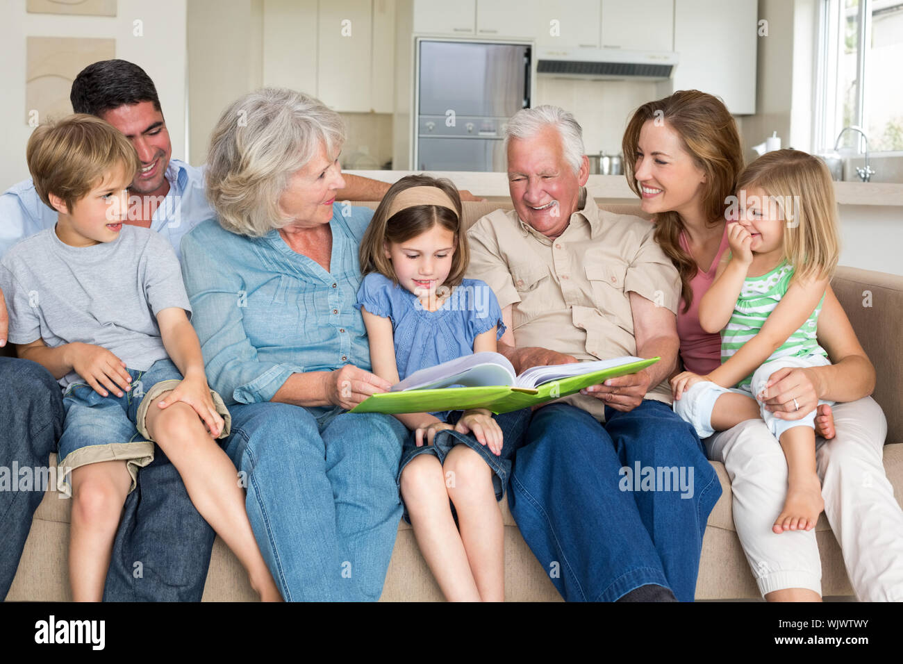 Multigeneration family reading storybook in living room Stock Photo - Alamy
