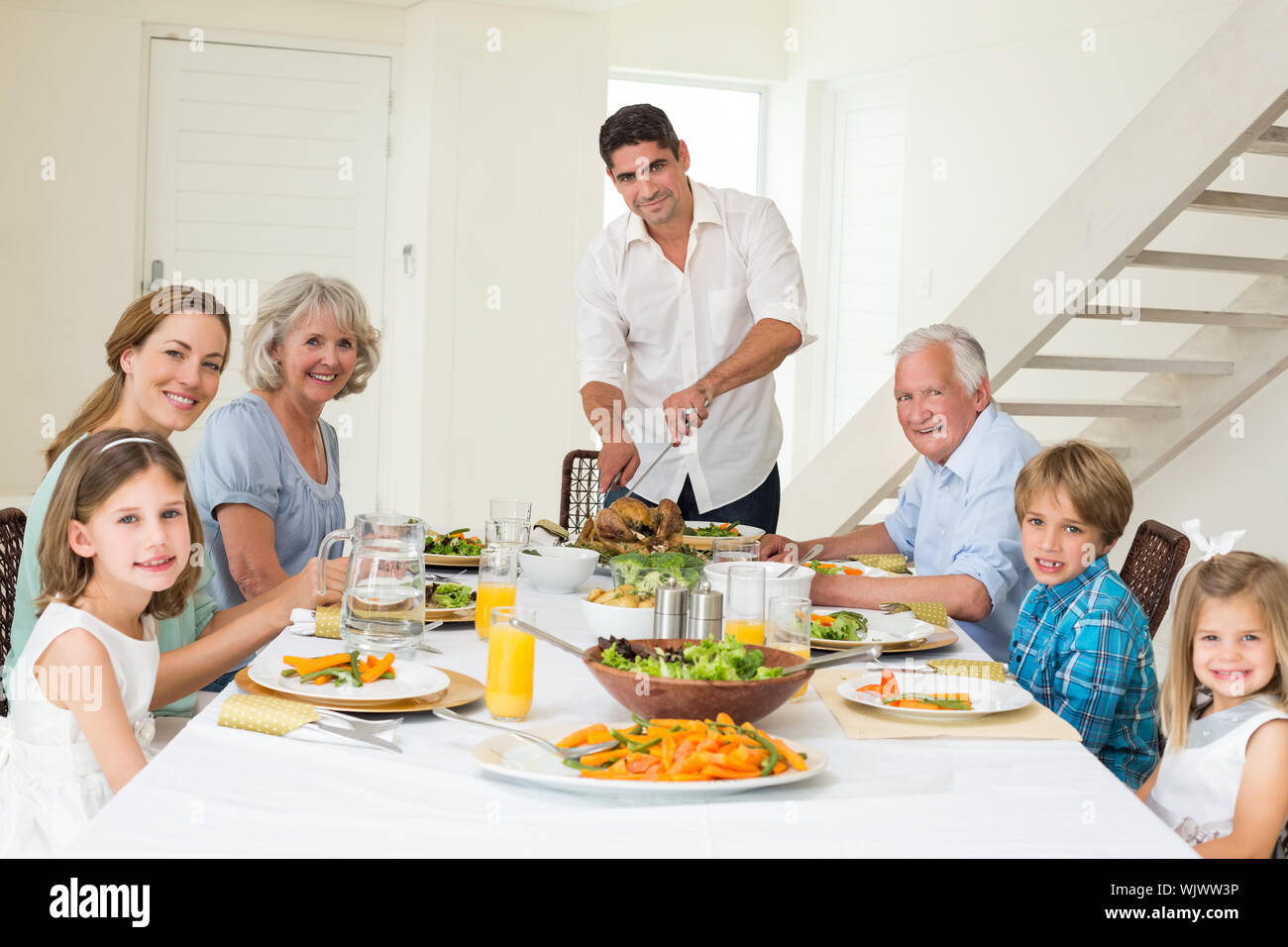 Portrait of smiling father serving meal to family at dining table Stock ...