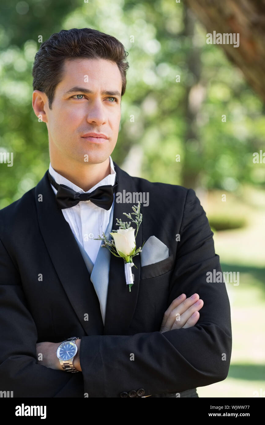Thoughtful young groom with arms crossed standing in garden Stock Photo ...
