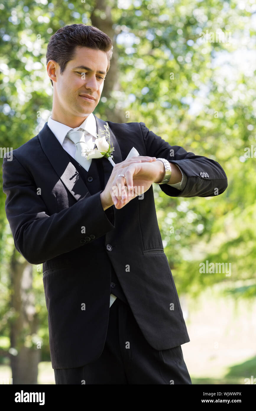 Young smart groom checking time in garden Stock Photo - Alamy