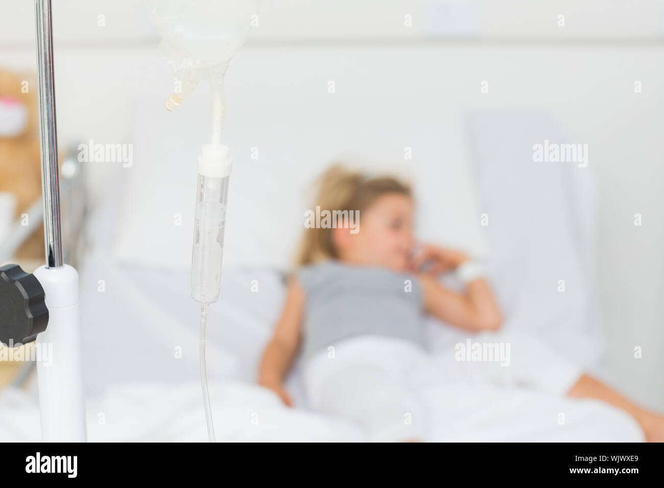 Focus on IV drip with sick little girl in hospital bed Stock Photo - Alamy