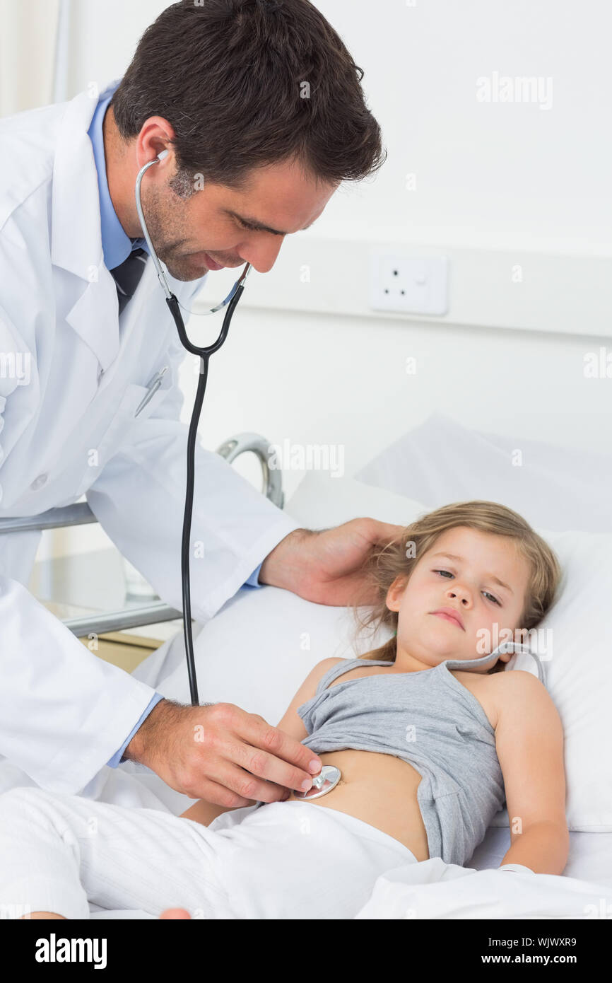 Male doctor examinig stomach of sick girl in hospital ward Stock Photo ...