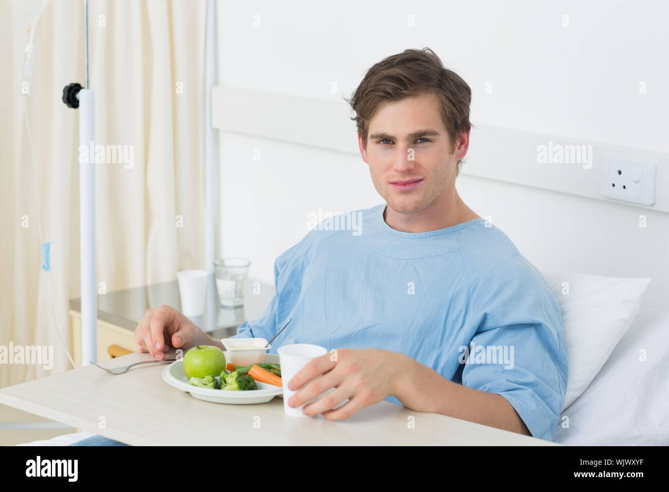 Portrait of handsome patient having meal on hospital bed Stock Photo ...