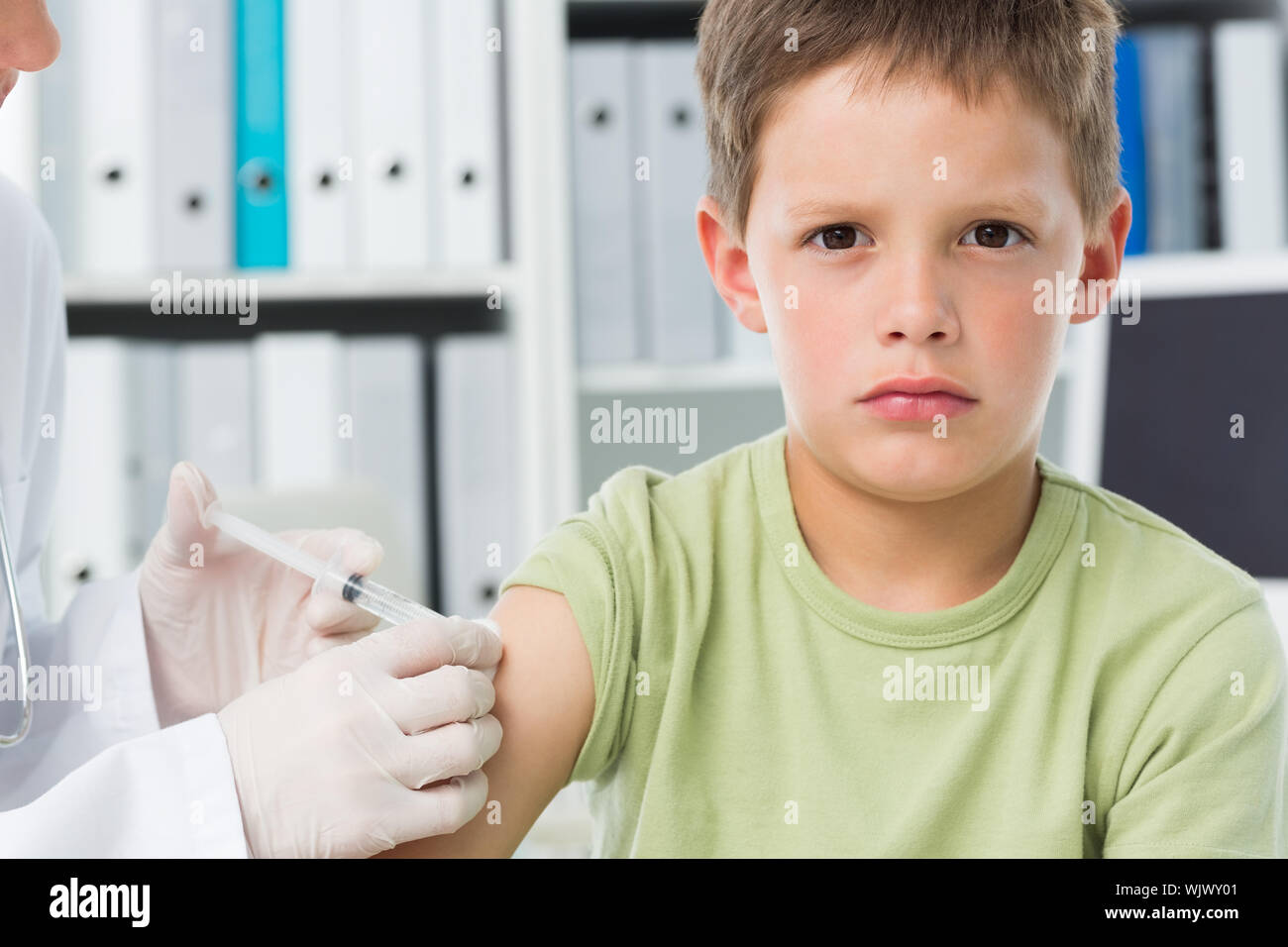 Portrait of boy receiving an injection by female pediatrician in clinic ...