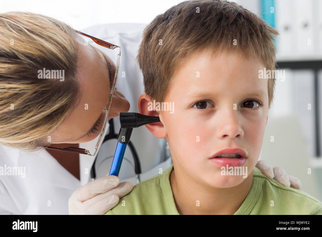 Closeup of little boy being examined by female doctor with otoscope in ...